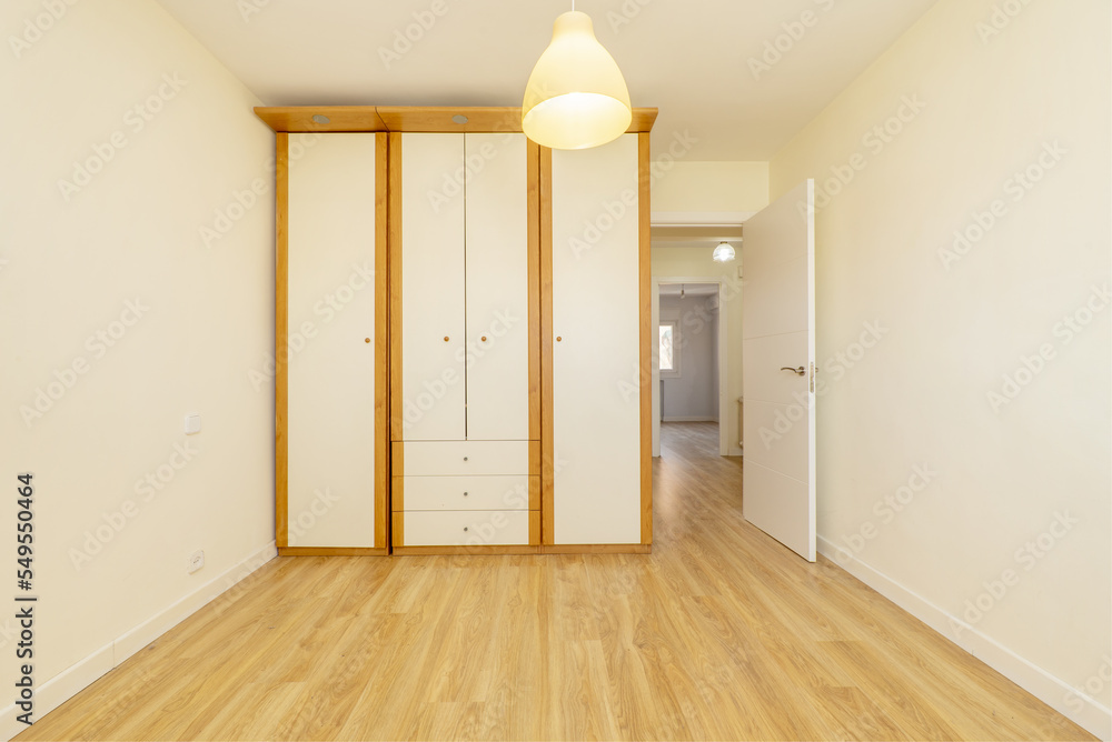 room with a built-in wardrobe with two-tone wooden doors and drawers in ...