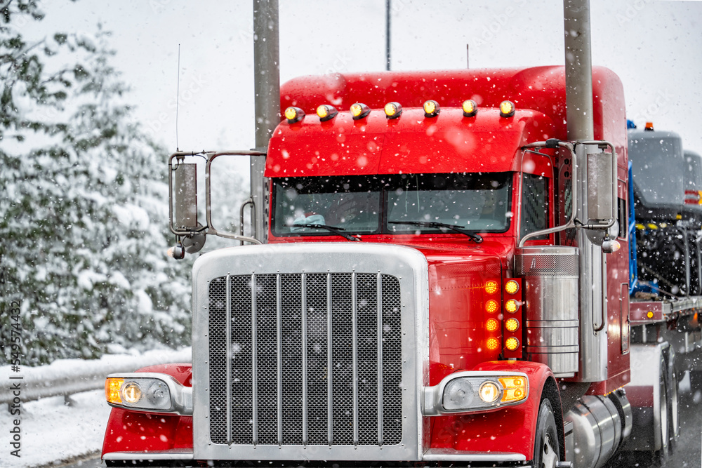 Stylish bright red classic big rig semi truck with turned on auxiliary ...
