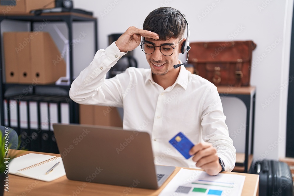 Young hispanic man working using computer laptop holding credit card ...