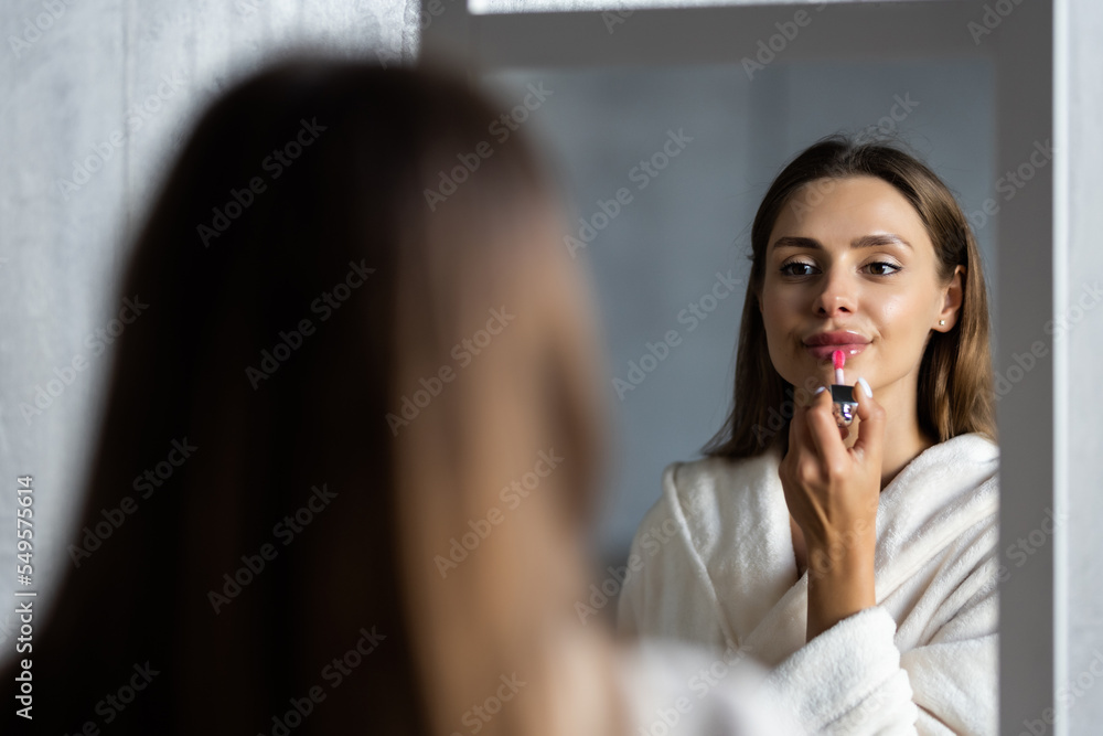 Female in bathrobe enjoy self-grooming in front of mirror holds ...