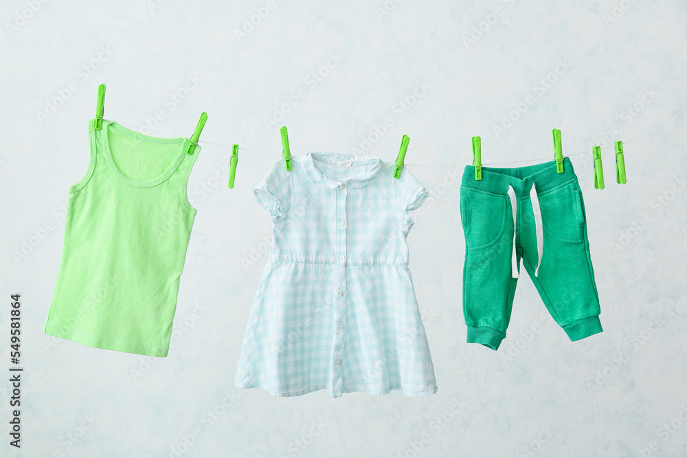 Baby clothes hanging on rope against light background Stock Photo ...
