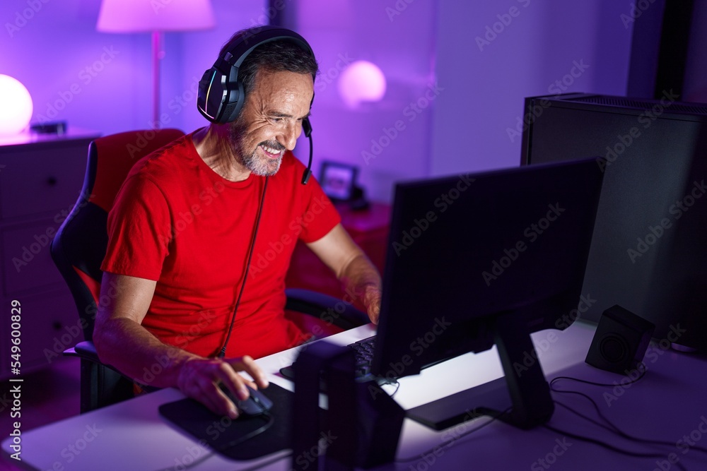 Middle age man streamer playing video game using computer at gaming ...