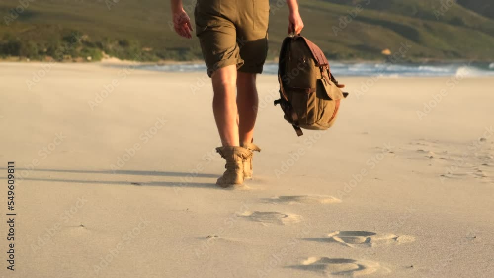 Man walking along beach to sea at golden sunset. men's feet in mountain ...
