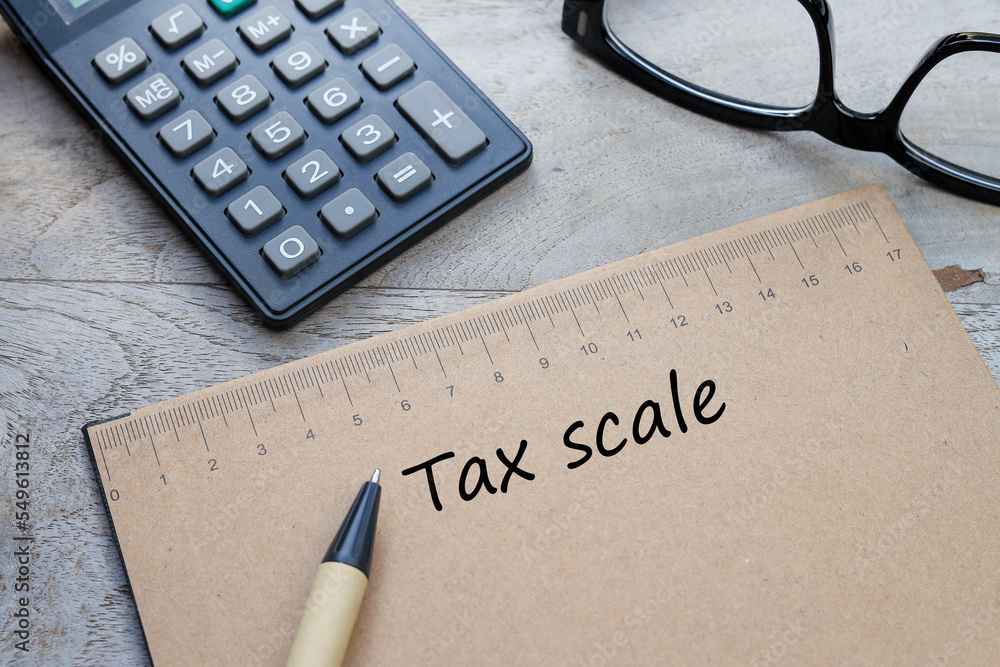 Tax Scale wordings below the scale with a pen, calculator, and ...