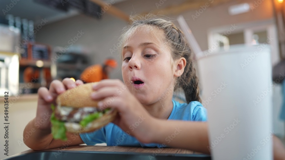 child kid eating a burger in a cafe. fast food nutrition health concept ...