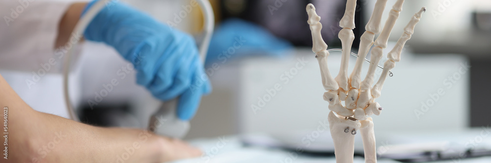 Poster Doctor do ultrasound of hand, skeleton hand model on desk ...