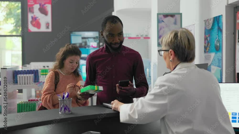 Young customers buying vitamins and drugs at pharmacy cash register ...