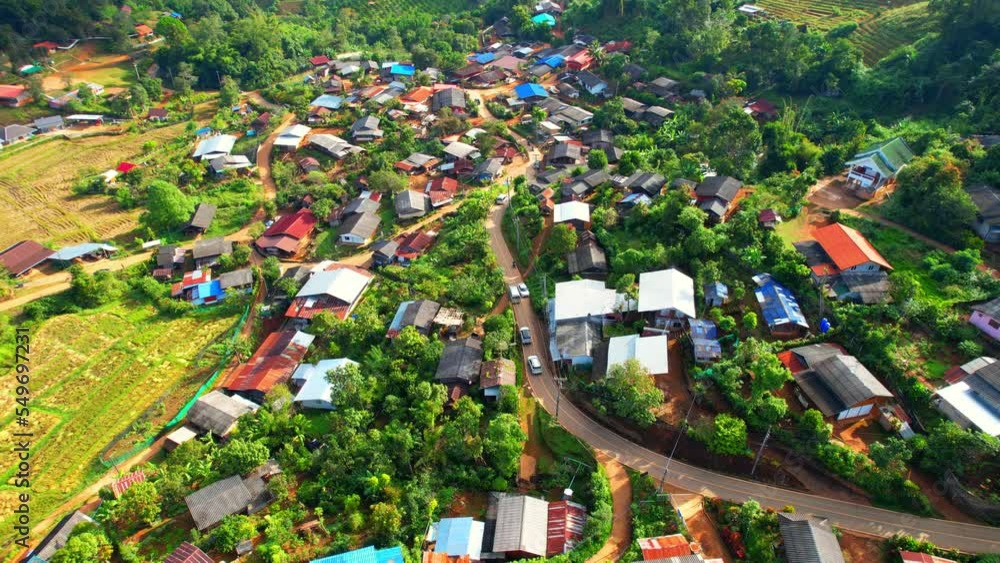 Aerial view over a hillside village and agricultural area during ...