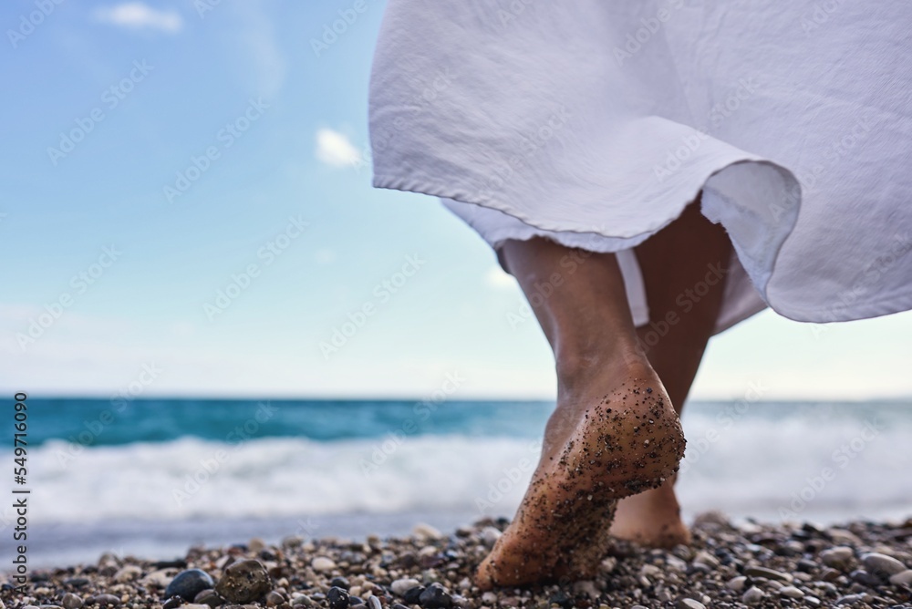 Women's feet in the sea. Close-up side view of a young woman's bare ...