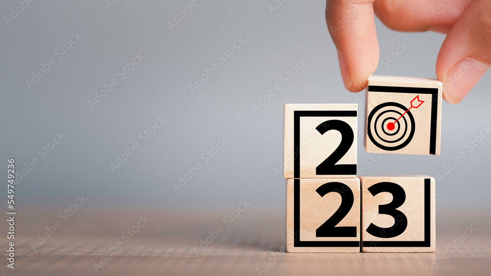 Target plan icon in wooden cubes stacking by hand and 2023 business ...
