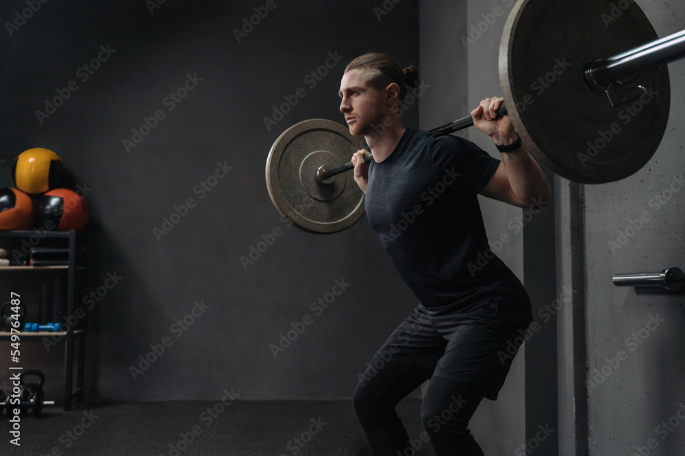 Crossfit athlete lifting barbell in dark workout gym. Functional and ...