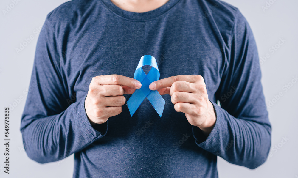 Men Hands Holding Blue Ribbon For Supporting People Living And Illness