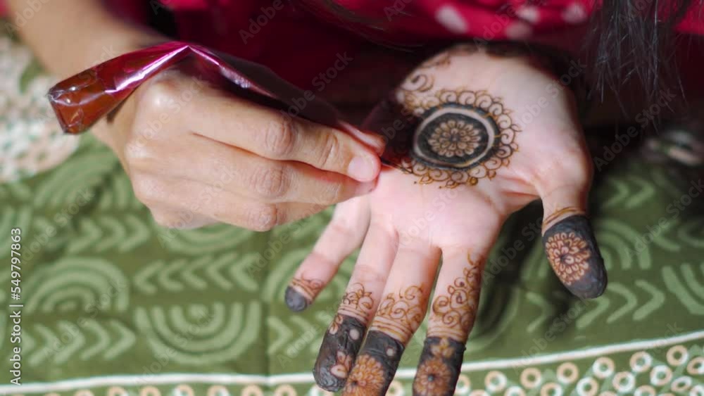 Close up shot of Hindu Indian girl applying Mehndi design in her hand ...