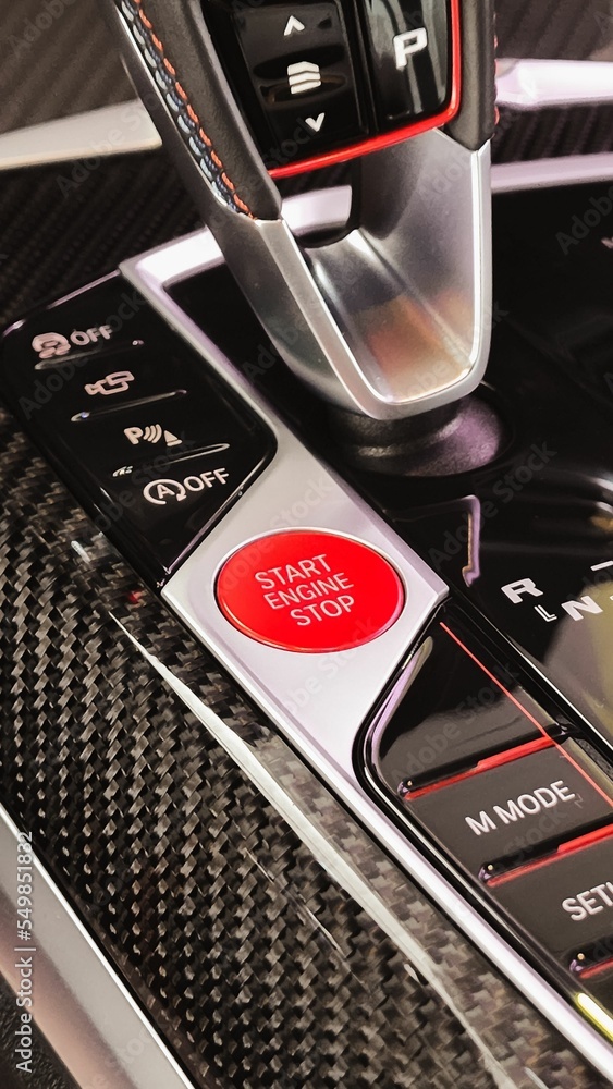Vertical shot of BMW M3 Competition Red Engine Start button on carbon ...
