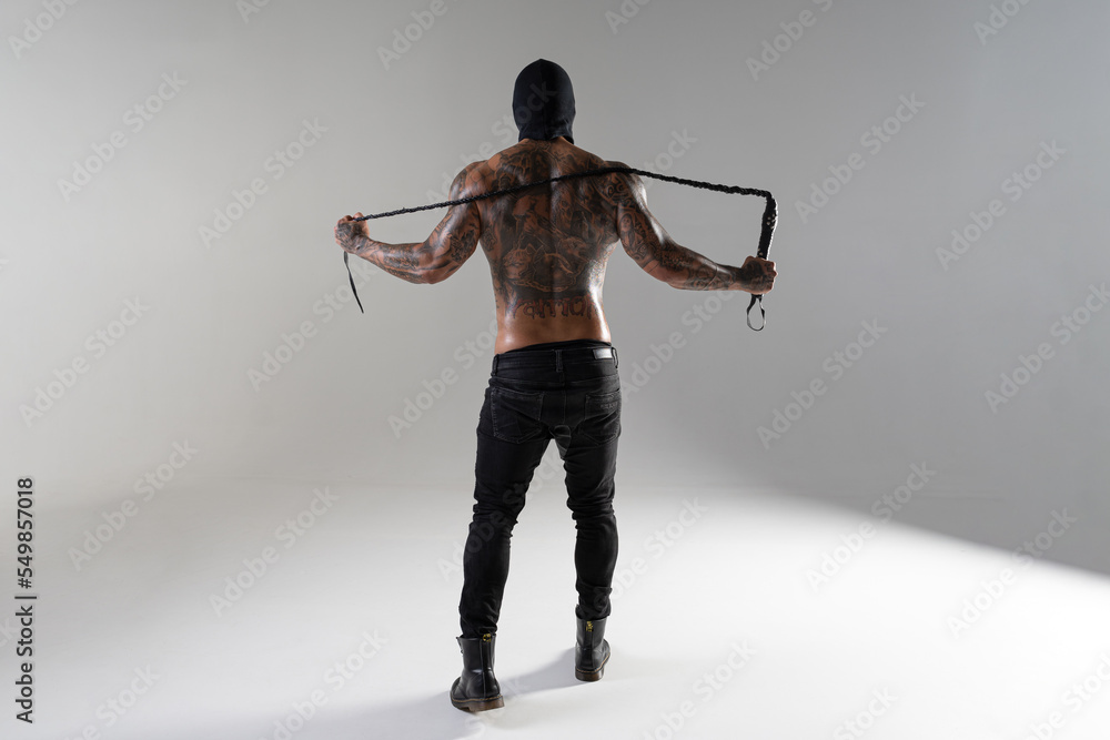 Muscular shirtless young man with whip in a mask.Brutal handsome man ...