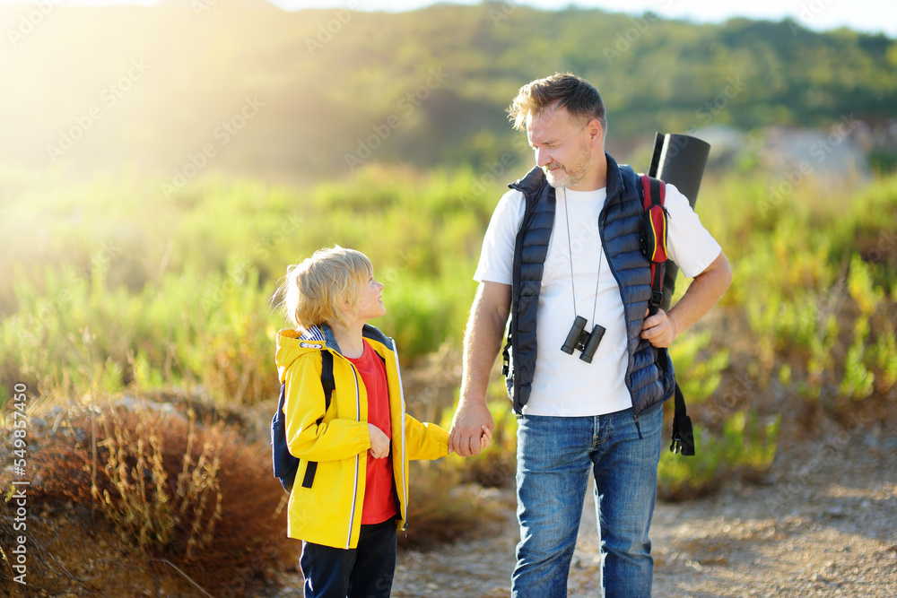 Cute schoolchild and his mature father hiking together and exploring ...