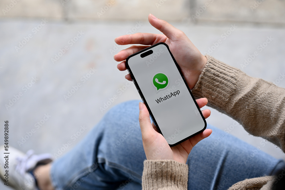 A female hand holding a smartphone with WhatsApp application logo on ...