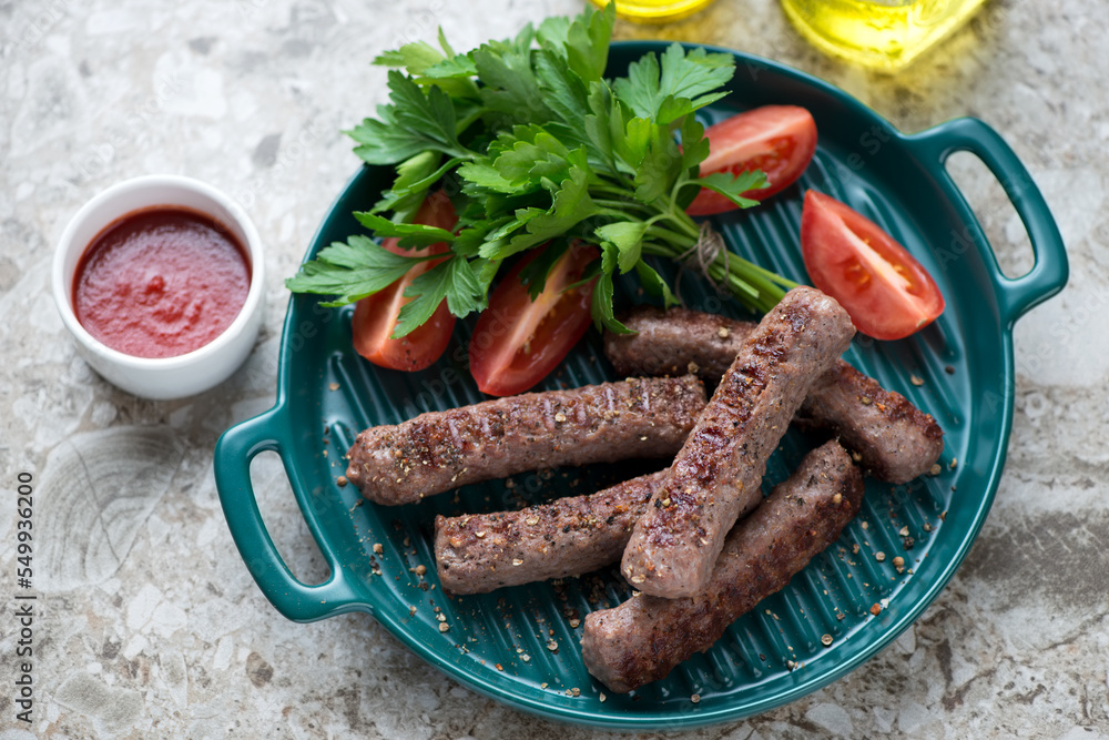 Green serving tray with grilled serbian cevapi or cevapcici sausages ...