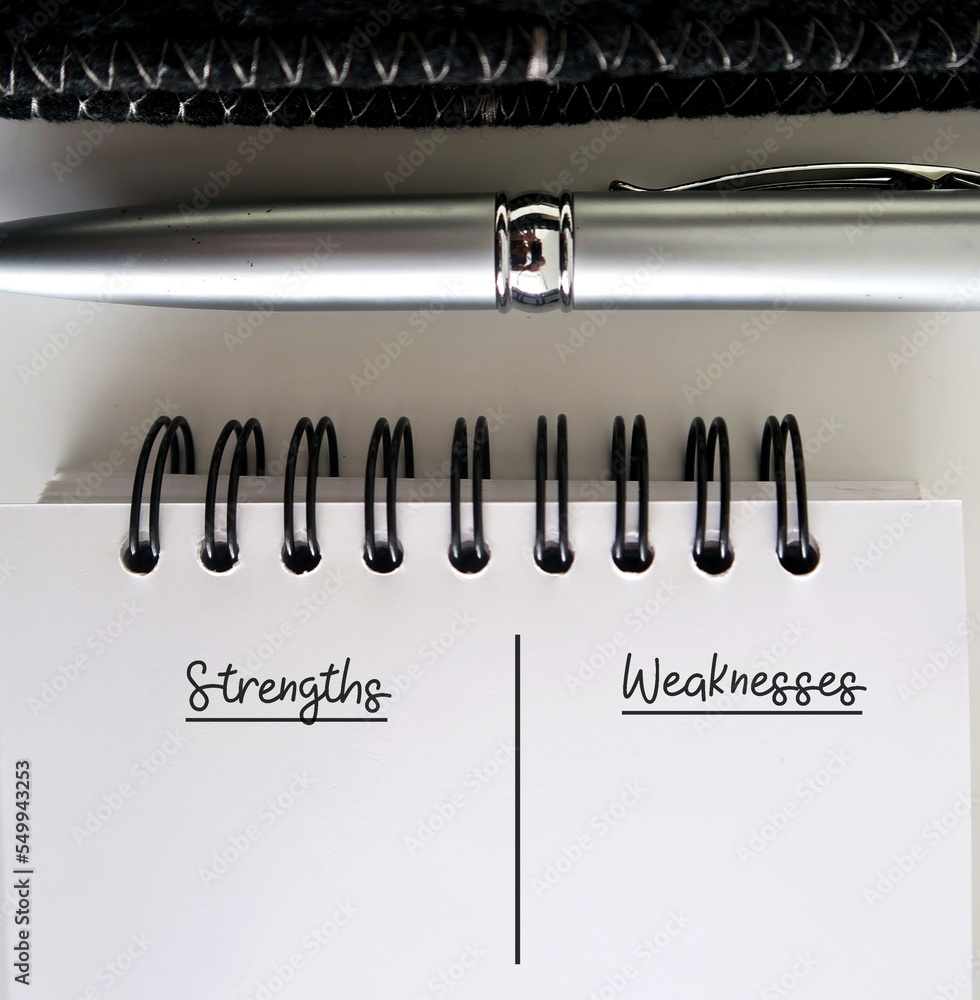 Pen and notebook on paper with text written STRENGTH WEAKNESSES ...