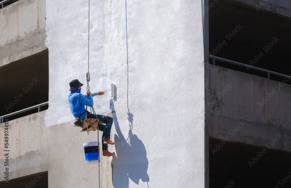 Asian construction worker rappelling to painting white primer on ...