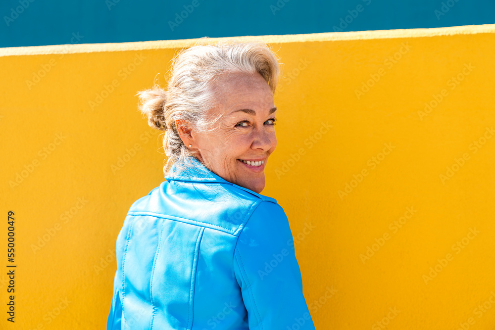 Happy mature woman looking over shoulder in front of wall Stock Photo ...