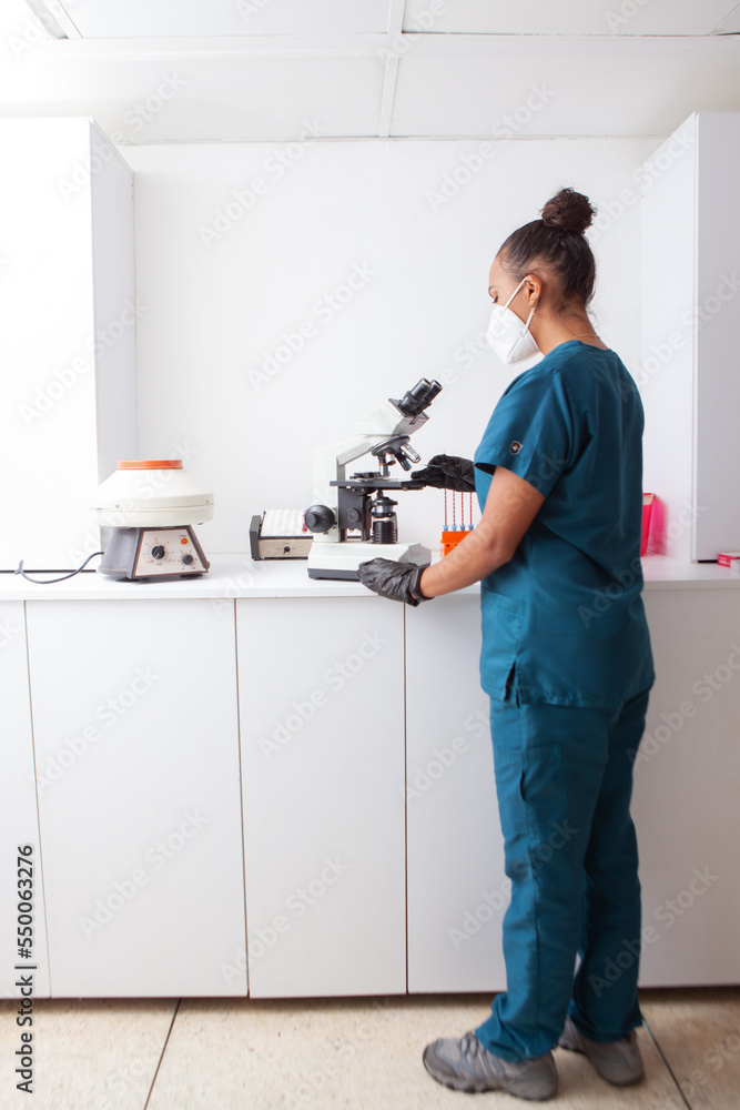 biotechnician woman placing a sample slide in a microscope full body ...