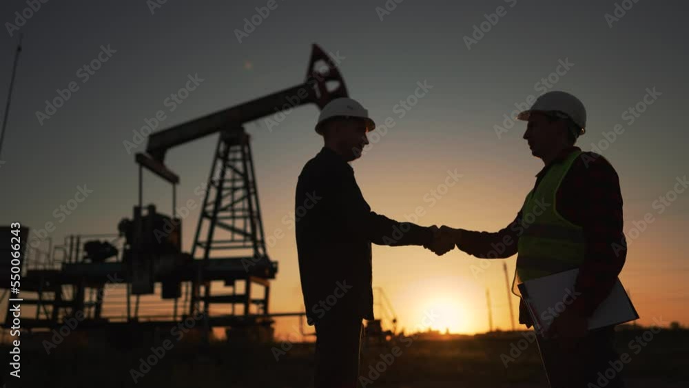 Teamwork.Oil engineer in helmet work with an oil pump.Silhouette of ...