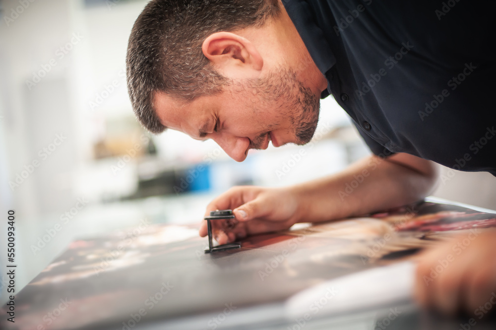 Young man in the process of printing used color scales and loupe and ...