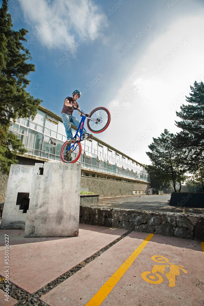a man with a bike standing on the back wheel of his bike over a ...