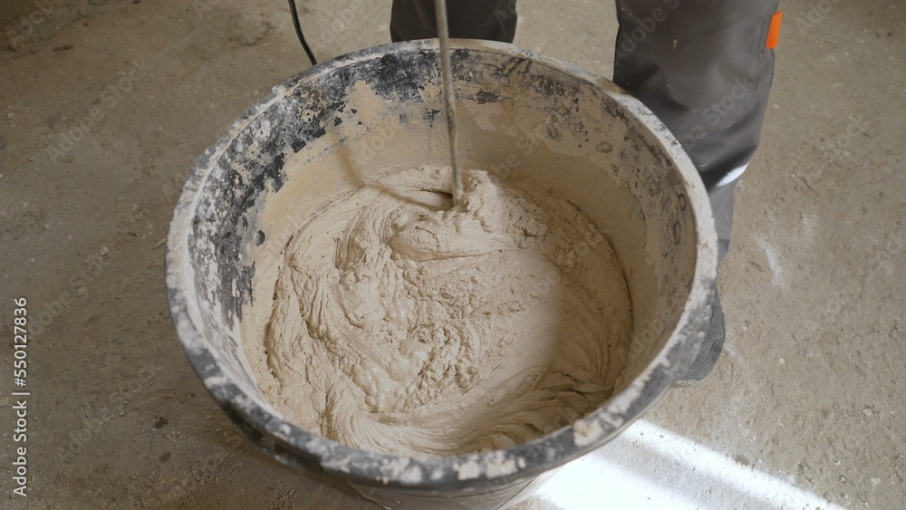 Mixing cement adhesive with a mixer in a bucket close-up, texture of a ...