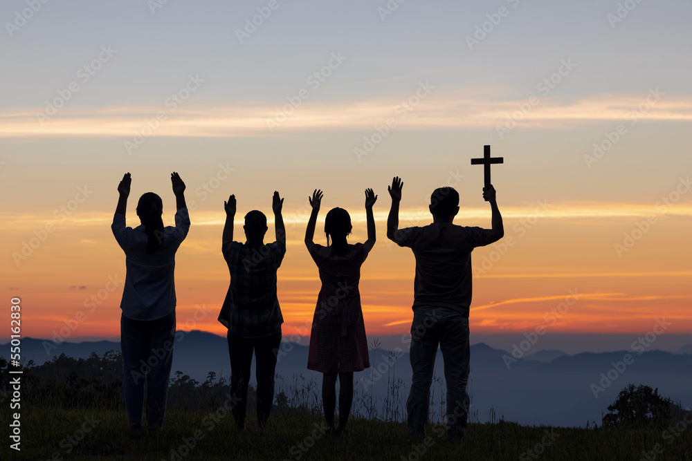 Silhouette family praying and holding Christian cross for worshipping ...