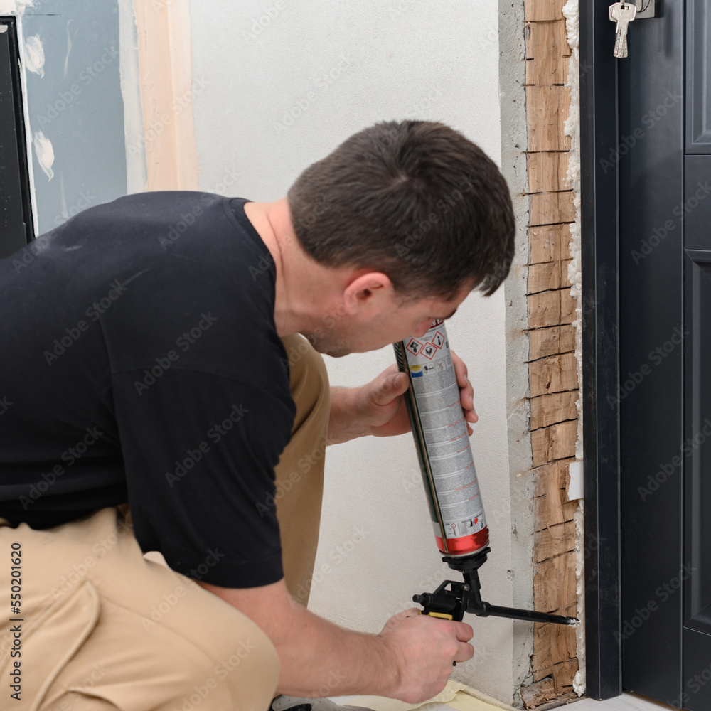 a man uses a spray gun with his hand and fills the gap with ...