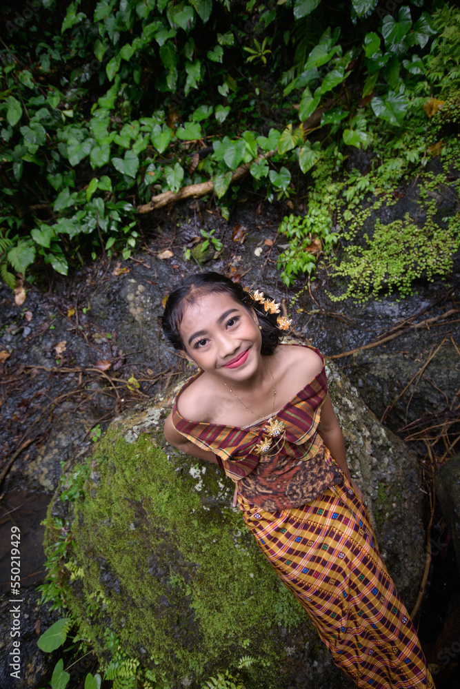 Portrait one girl in classic Balinese clothes pose at waterfall, see ...