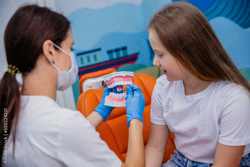 A female dentist shows a girl of European appearance 10 years old a ...