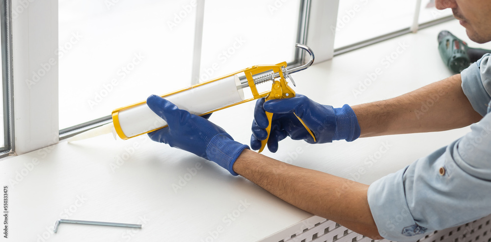 Construction worker sealing window with caulk indoors Stock Photo ...