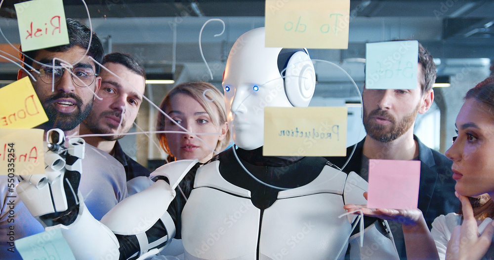 Diverse team of project discussing plans and to-do notes with robot ...