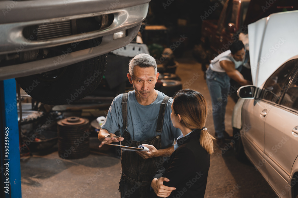 Senior male mechanic in uniform checking and diagnostic car while ...