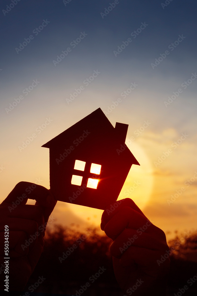Foto de Hands holding paper house on sunset sky, family home, homeless ...