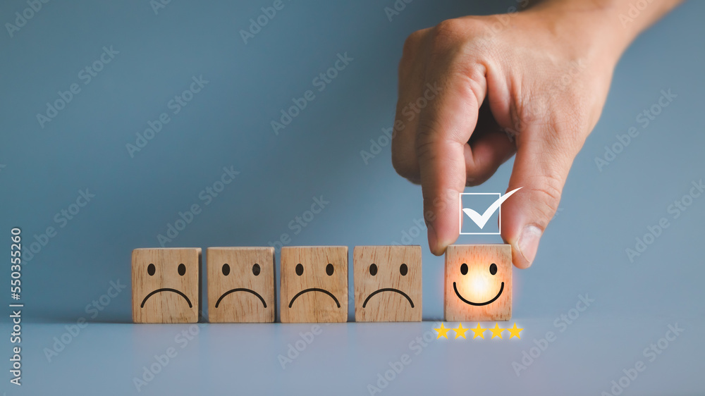 Hand holding a wooden block with smiley face icon and check mark symbol ...