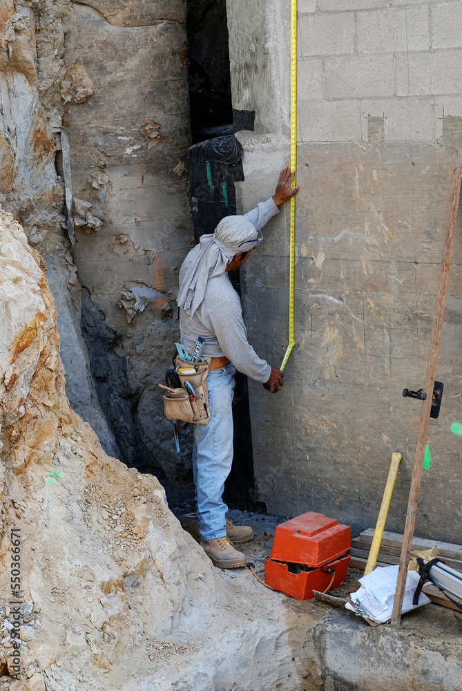 Construction worker measuring the height of a retaining wall Stock ...
