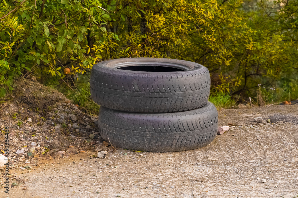An old tire discarded in the trash, sealed with gray tape. Pollution of ...