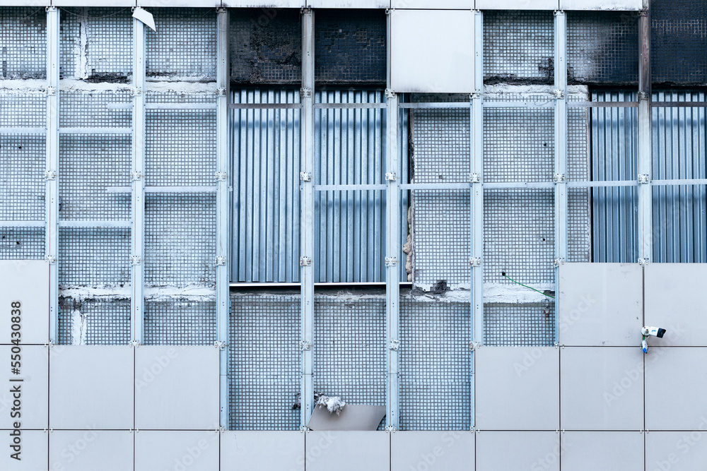 Broken, badly fixed wall of an industrial building. Fallen off cladding ...