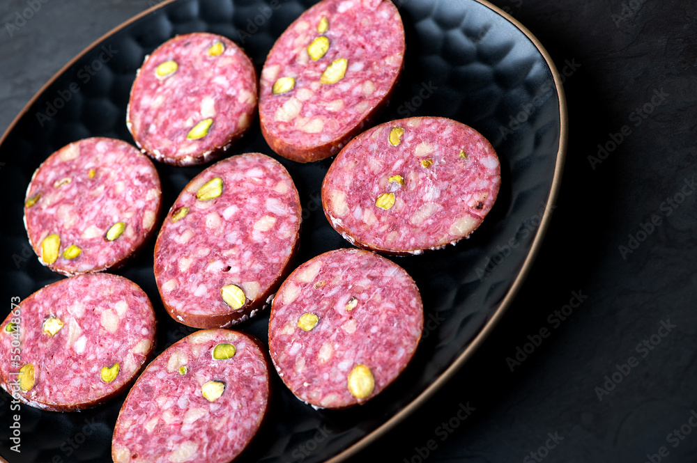 Traditional smoked salami sausage with spices and pistachios on black ...
