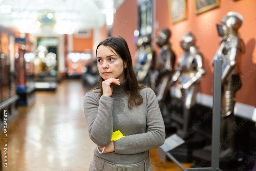 Portrait of interested adult female tourist visiting exhibition of ...