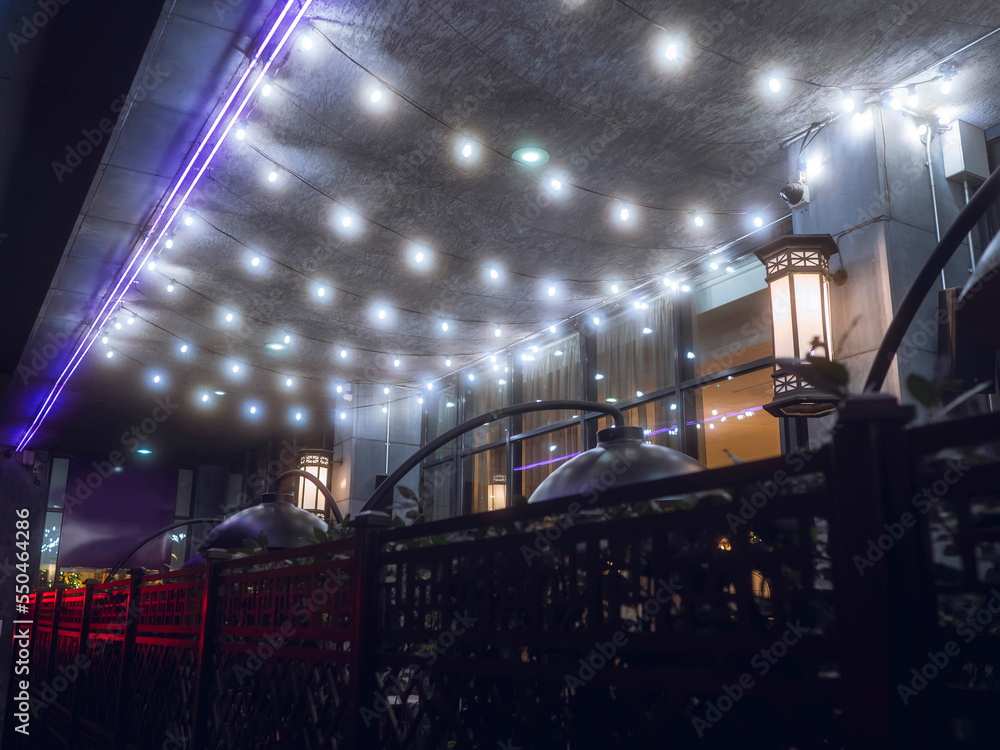 Glowing illuminated lights over open veranda of a bar or night club ...