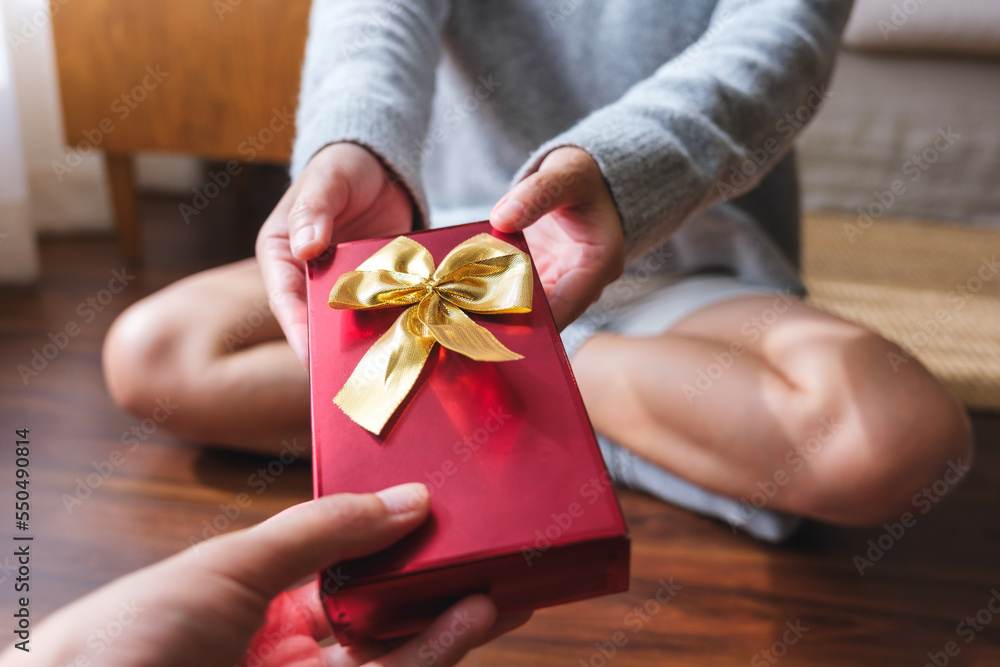 Closeup image of a couple people giving and receiving a gift box to ...
