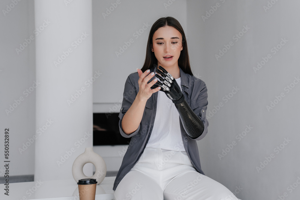 Attractive brunette caucasian girl in grey shirt and white pants learning how to use artificial ...