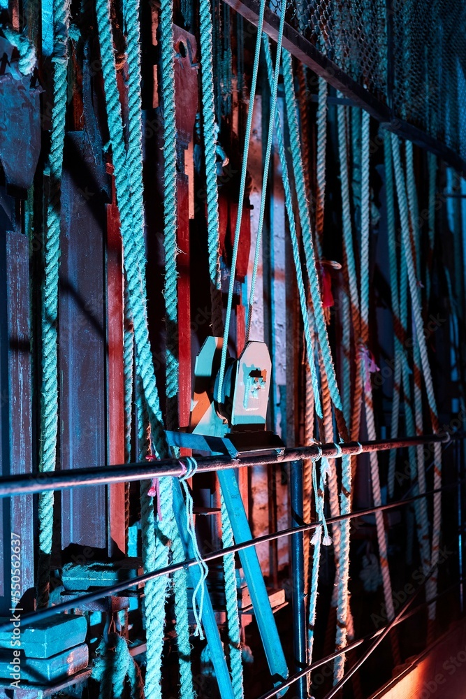 Cable and chain rigging backstage in a theater. Vertical lines. Neon ...
