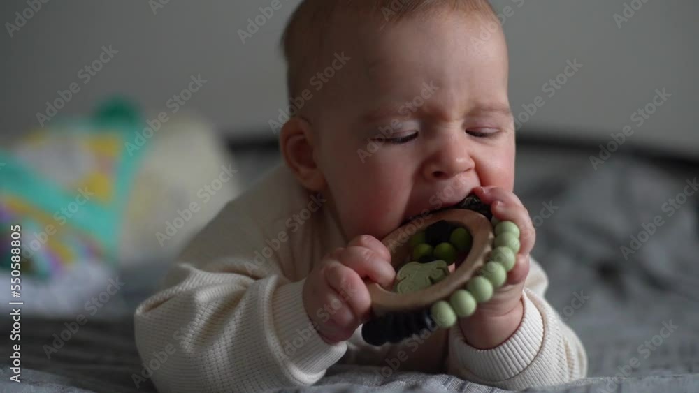 baby chewing teether toy. Infant growing first tooth. Boy biting toy on ...