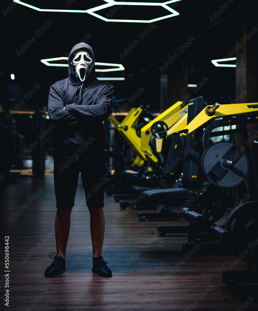Man in scary mask in gym standing. Dark male person in halloween mask ...